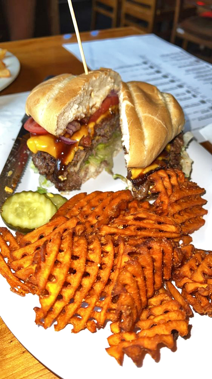 The burger arrives like a work of art – melted cheese cascading down the sides, with those seasoned fries demanding equal attention.