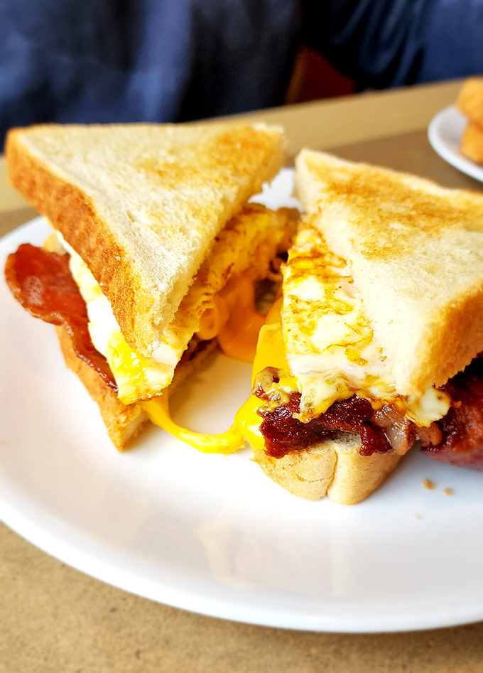 The breakfast sandwich in its natural glory &ndash; melty cheese, perfectly cooked egg, and bacon creating the holy trinity of morning deliciousness.