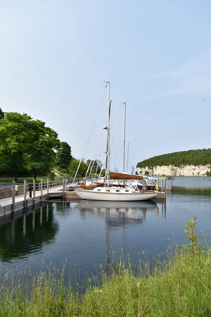 Not a bad place to drop anchor, eh? Sailboats find peaceful harbor where iron-laden vessels once departed, nature's tranquility replacing industrial bustle.