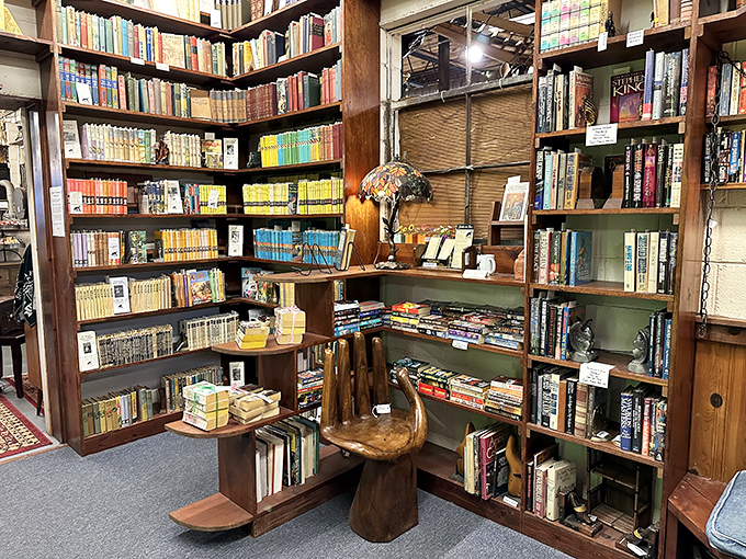 A bibliophile's dream corner where color-coded shelves hold literary treasures. That wooden stool practically invites you to sit and sample a few pages.
