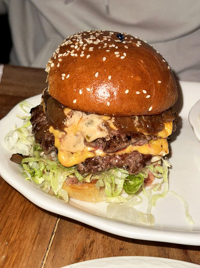 This isn't just a burger; it's a skyscraper of beef and cheese architecture that requires both hands, several napkins, and zero shame.