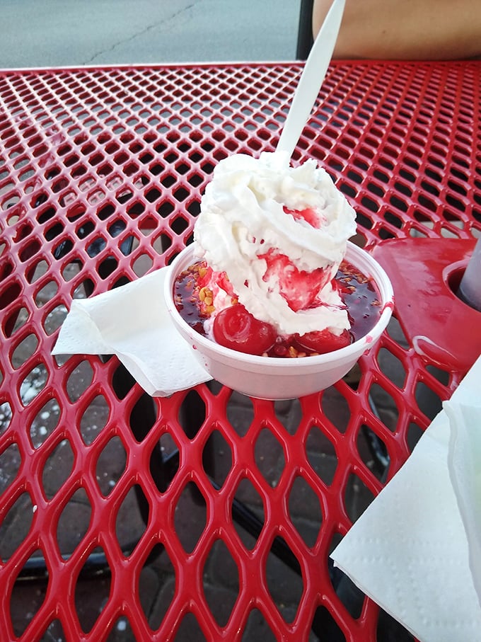A cherry sundae that looks like it escaped from a 1950s soda fountain. That whipped cream mountain could use its own climbing permit.