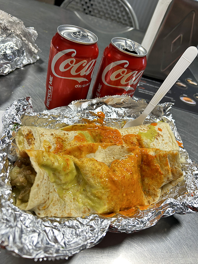 Two Coca-Colas standing guard over a foil-wrapped treasure. The sauce seeping through hints at the flavor explosion waiting inside&mdash;anticipation never tasted so good.