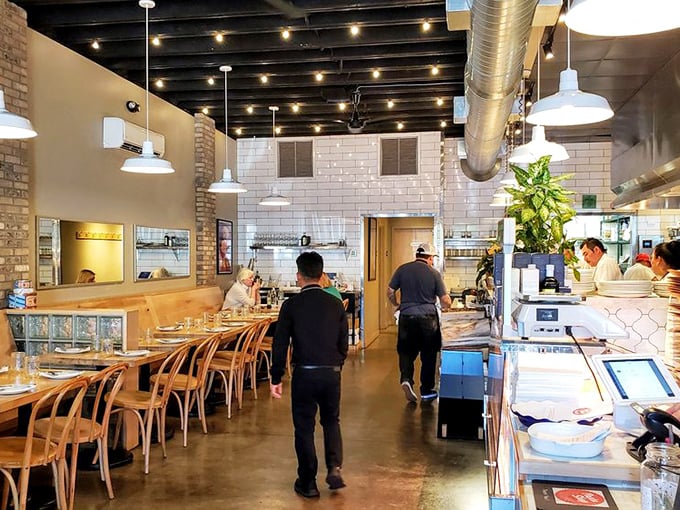The dining room hums with the symphony of happy eaters. White subway tiles and exposed brick create the perfect backdrop for pasta appreciation.