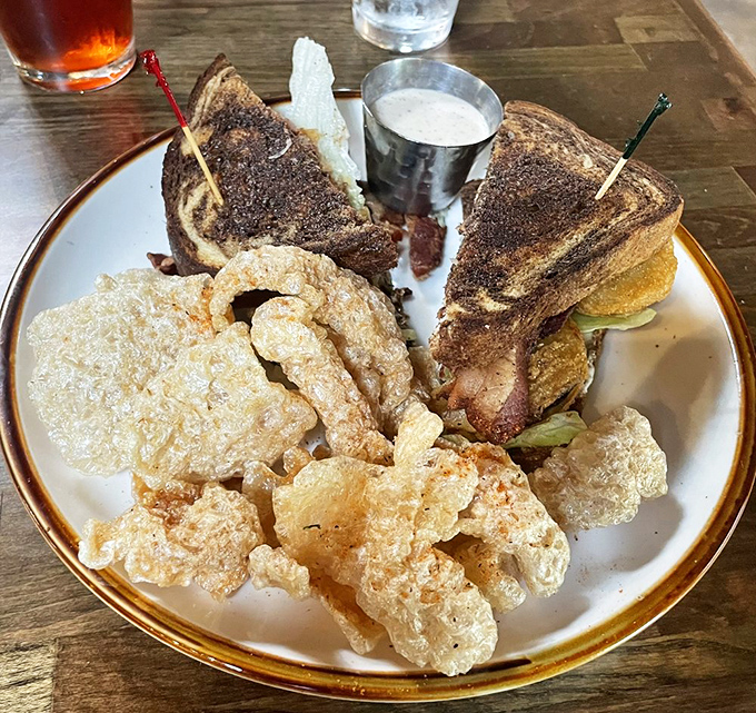 The Fried Green Tomato BLT elevates a Southern classic with crispy pork rinds on the side—proof that side dishes deserve their moment in the spotlight too.
