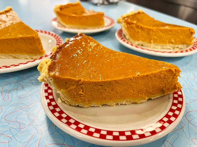 Pumpkin pies lined up like autumn ambassadors on their checkered-trim plates, each slice promising a direct route to nostalgic comfort.
