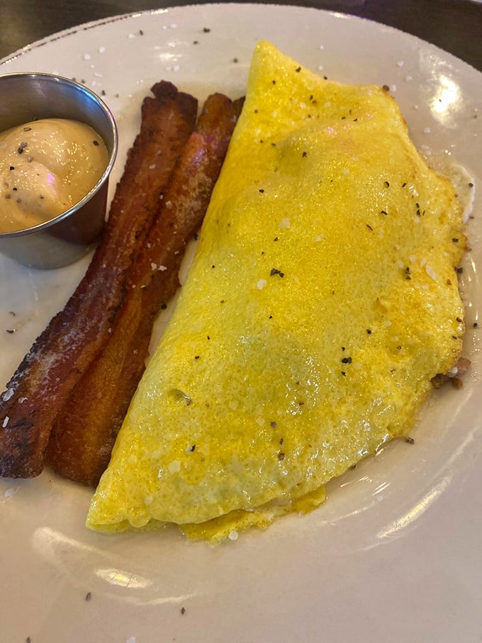 Yellow on the outside, flavor explosion on the inside. This omelet and its perfectly crisp bacon sidekick demand your full attention.