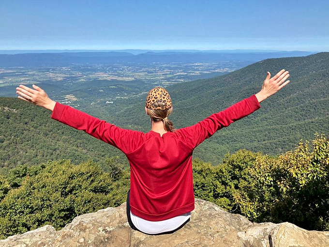 The universal gesture of mountain joy: arms outstretched above the valley. Some views simply demand more than a polite nod of appreciation.