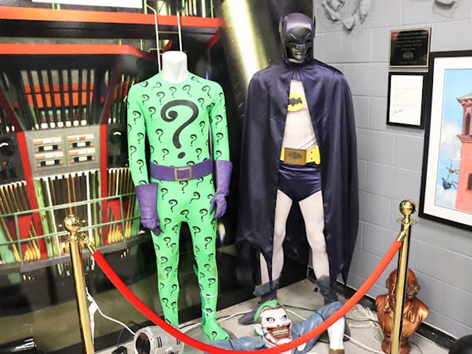 The Riddler and Batman costumes stand in silent conversation, a permanent freeze-frame of the eternal question: can you really trust anyone wearing that many question marks?