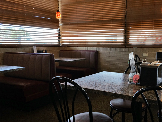 Wooden booths bathed in warm light from amber pendant lamps create the perfect setting for serious chicken contemplation. No distractions, just anticipation.