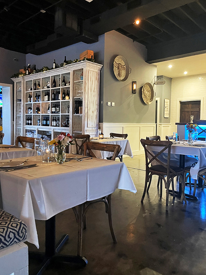 Wine bottles stand at attention in rustic cabinets while white tablecloths await their next guests. The dining room whispers "special occasion" without shouting it.