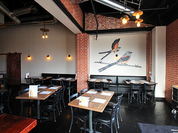 Bird art watches over diners like a whimsical guardian. The brick walls and warm lighting create the perfect backdrop for food-induced happiness.