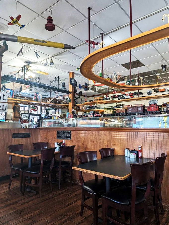 The dining room where time slows down as model trains speed up. Wooden booths and tables create intimate spaces beneath an ever-changing ceiling of miniature locomotives.