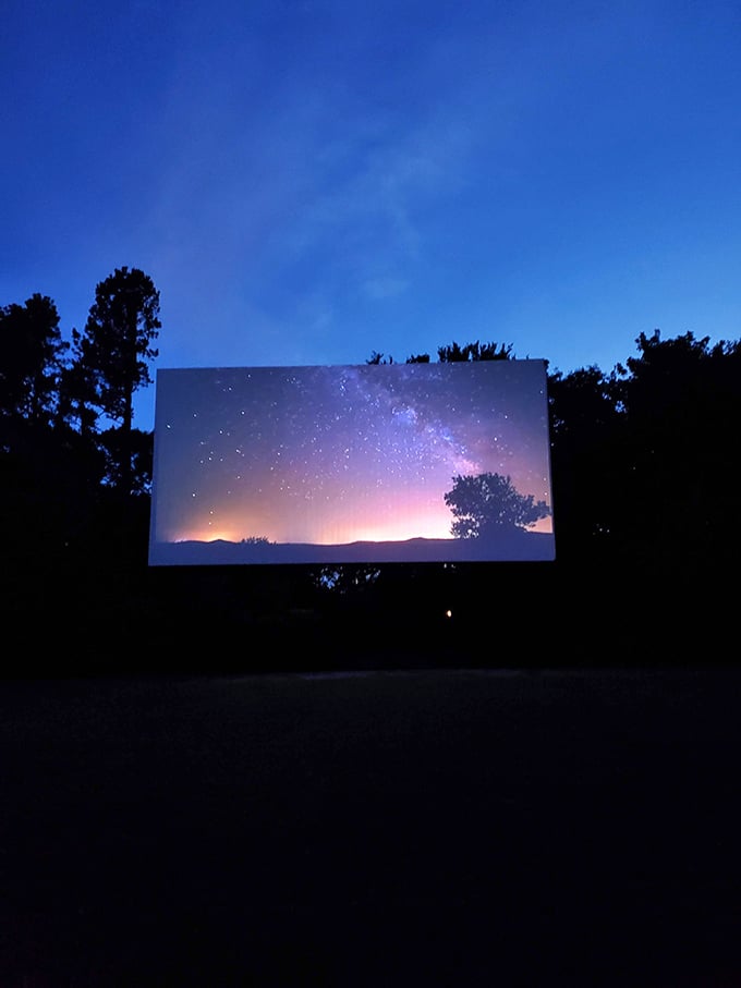 The massive screen glows with twilight magic, stars above competing with stars on screen in this perfect rural theater.