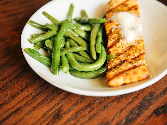 Simple elegance on a plate: perfectly grilled salmon alongside vibrant green beans&mdash;proof that pub food isn't all about indulgence.