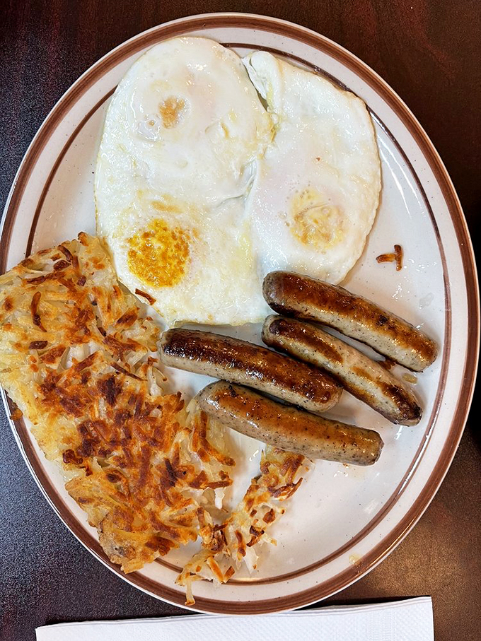 The breakfast trifecta: farm-fresh eggs, sizzling sausage links with that perfect snap, and hash browns crisped to golden perfection.