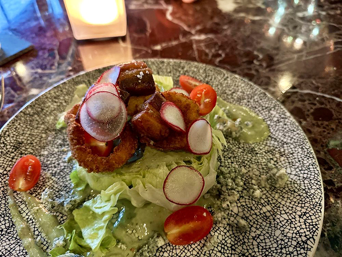 A wedge salad reimagined&mdash;crisp lettuce crowned with golden-fried delights and radish coins that add both crunch and visual pop.