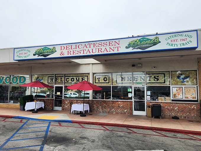 The classic storefront of Brent's Deli beckons with its nostalgic charm. Those red umbrellas aren't just for show&mdash;they're gateways to sandwich paradise.