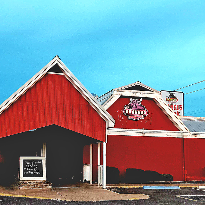 The iconic red barn exterior of Brangus Steakhouse stands out against the Arkansas sky like a beacon for hungry travelers seeking serious steak satisfaction.