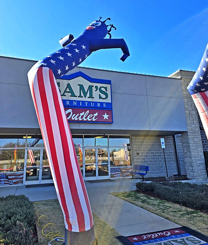 The iconic red entrance of Sam's Furniture stands out like a Broadway marquee, complete with a patriotic inflatable tube man welcoming shoppers to the furniture wonderland.