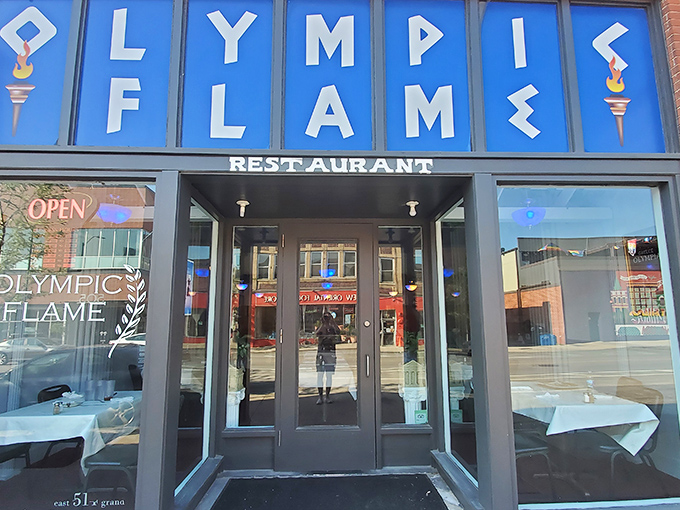 The blue signage of Olympic Flame beckons like a Mediterranean lighthouse amid Des Moines' brick buildings. Greek cuisine awaits!