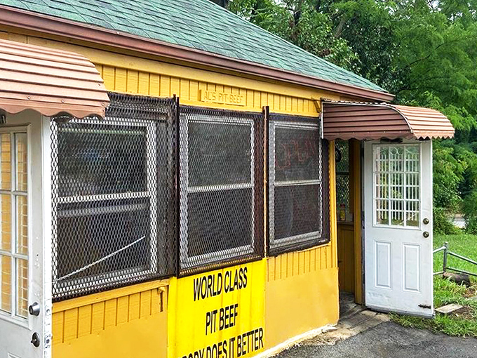 The humble yellow shack with stacked firewood speaks volumes: real pit beef doesn't need fancy digs when the smoke does the talking.