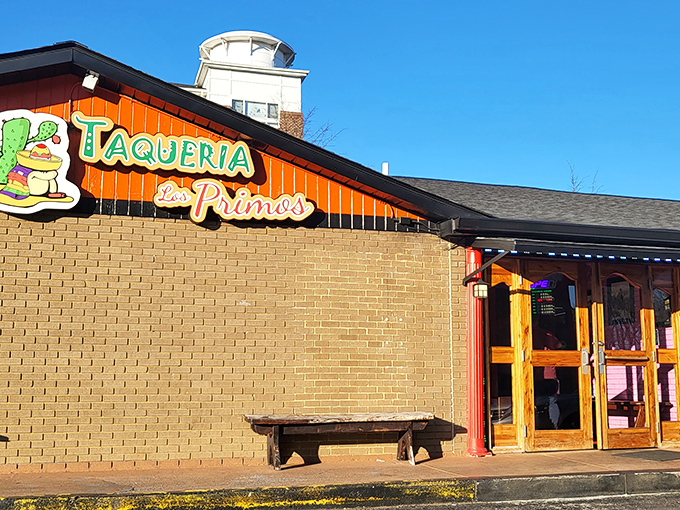 The unmistakable orange facade of Taqueria Los Primos stands out like a culinary lighthouse, beckoning hungry travelers with its colorful benches and promise of authentic flavors.