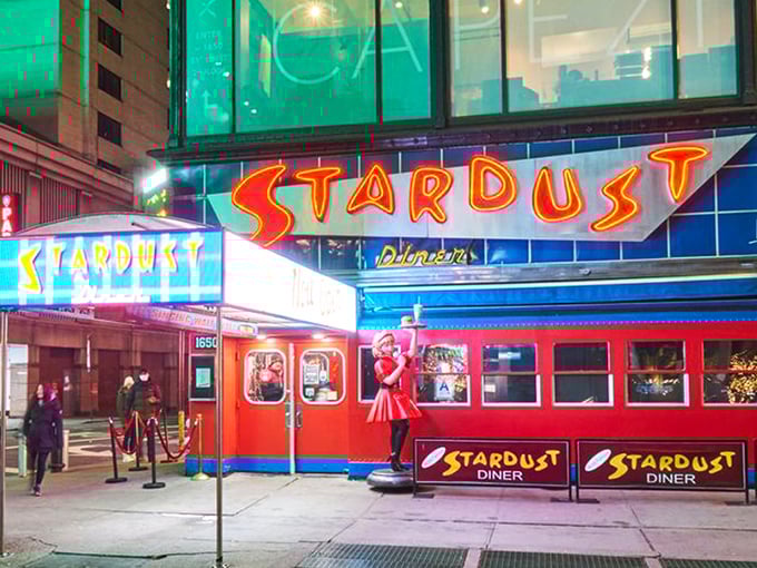 The neon-lit entrance to Ellen's Stardust Diner stands out like a Broadway marquee, promising both sustenance and showmanship in the heart of Times Square.