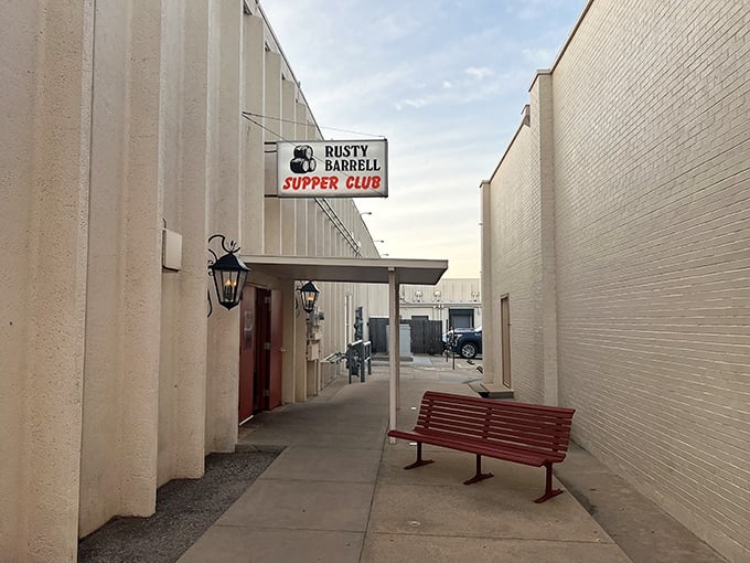 The unassuming entrance to Rusty Barrell Supper Club proves the old adage: never judge a steak by its storefront. That red bench? Your waiting room to carnivore heaven.