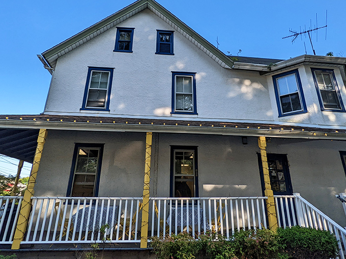 The white farmhouse with blue trim and wrap-around porch isn't trying to be fancy, but that rooster sign is basically saying "chicken paradise ahead!"