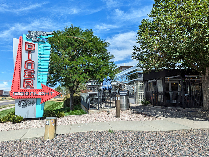 That neon sign doesn't whisper&mdash;it announces with retro swagger: "Hungry humans, your comfort food paradise awaits!" The turquoise and red color scheme practically sings against the Colorado sky.