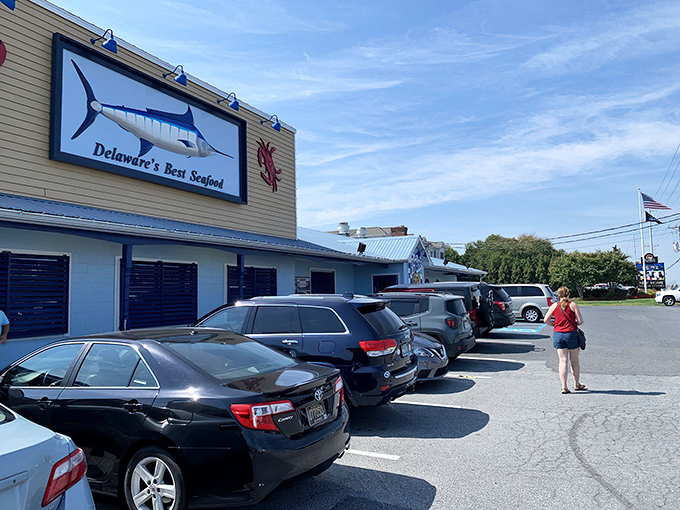 The blue and white checkered sign beckons like a coastal lighthouse, promising seafood treasures within this unassuming Rehoboth Beach institution.