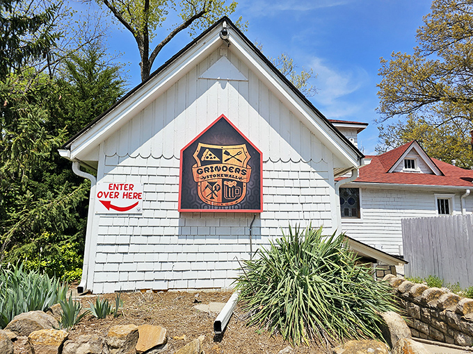 The charming cottage-like exterior of Grinders Stonewall beckons with its red-trimmed sign and helpful "ENTER OVER HERE" arrow—like your coolest friend's secret hideaway.
