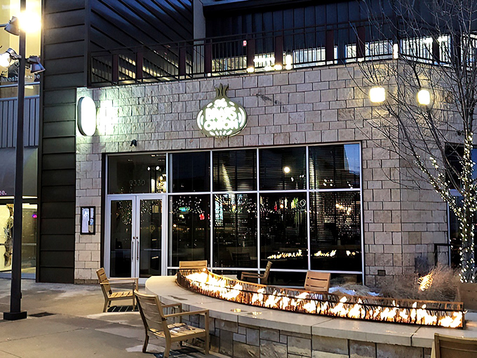 The Brass Onion's inviting exterior glows at twilight, with a cozy fire feature that practically whispers, "Come in and stay awhile."