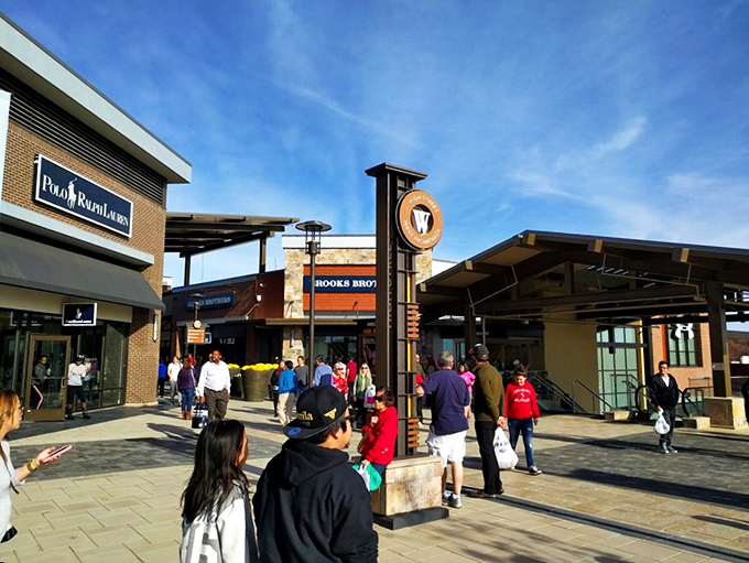 The grand entrance to Clarksburg Premium Outlets stands like a retail Colosseum, beckoning bargain hunters with promises of designer treasures within.