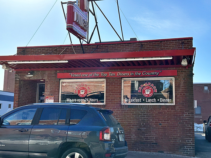 The iconic Red Arrow Diner sign beckons hungry travelers like a neon lighthouse in a sea of Manchester brick. Classic Americana at its finest. 
