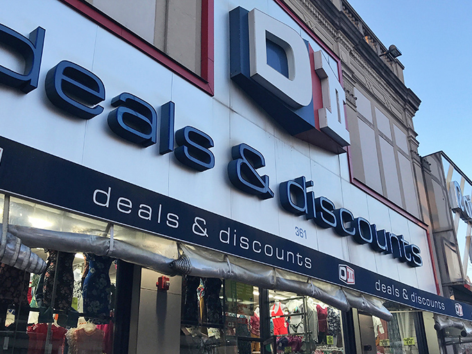 The blue and red signage of DII Deals & Discounts beckons like a siren song to bargain hunters navigating the urban landscape of Jersey City.
