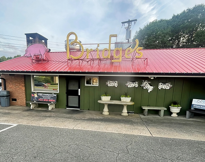 The iconic red roof and vintage sign of Red Bridges Barbecue Lodge stand as a beacon for hungry travelers. This Shelby landmark has been calling barbecue pilgrims home since 1946.