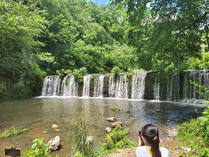 Nature's perfect curtain call &ndash; water cascades over a wide ledge, creating a serene backdrop that makes even smartphone photographers look like Ansel Adams.