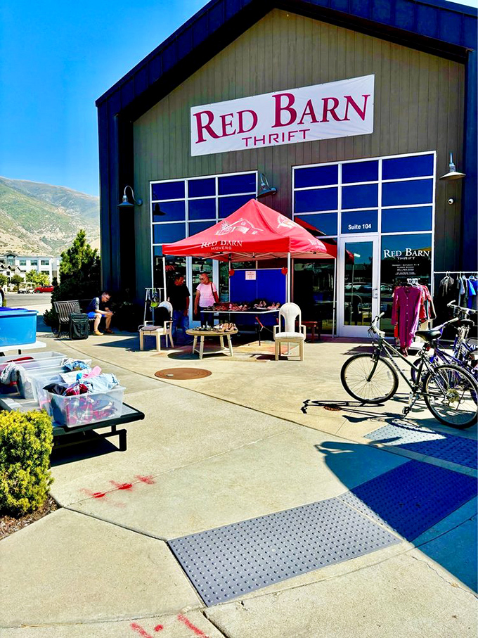 The iconic Red Barn Thrift stands proudly against Utah's mountain backdrop, colorful umbrellas inviting treasure hunters to step inside this Farmington gem.