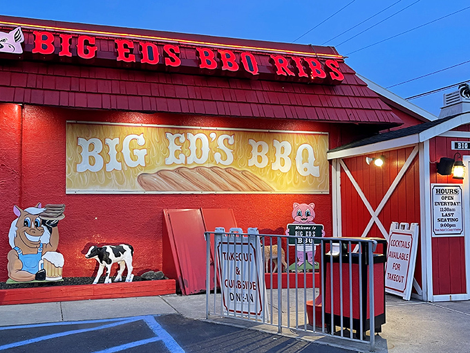 The barn-red exterior of Big Ed's BBQ stands out like a beacon for hungry travelers, complete with whimsical pig and cow cartoons that promise delicious things inside.