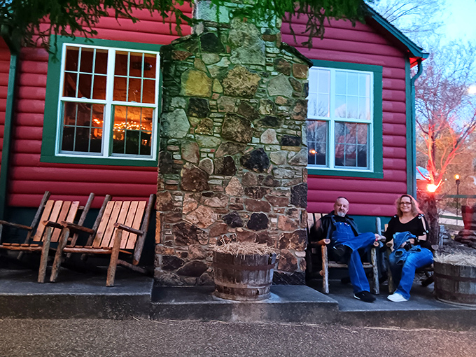 The crimson log cabin emerges from lush Ozark greenery like a storybook setting&mdash;complete with stone chimney and verdant landscaping that whispers "come on in."