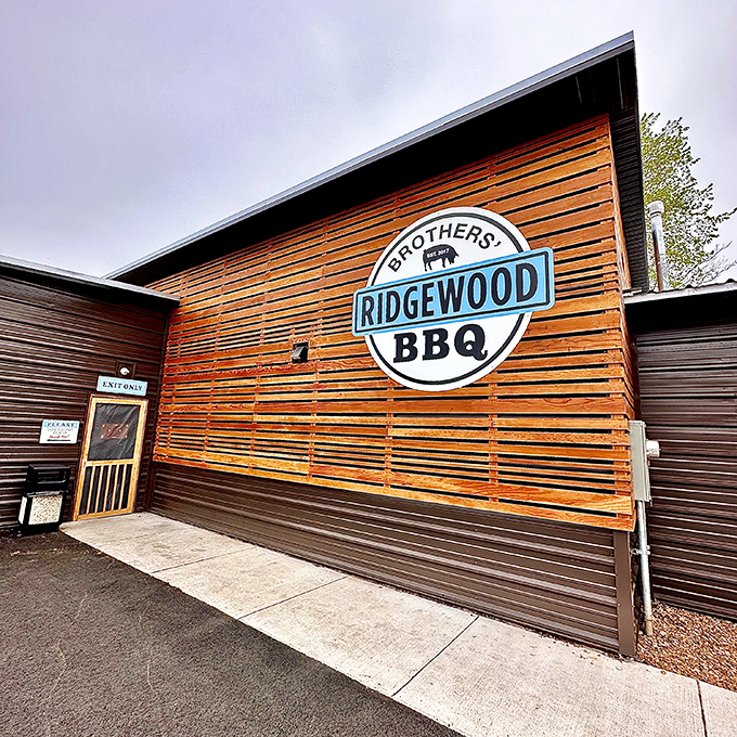 The modern wooden facade of Ridgewood Brothers BBQ stands like a beacon of hope for hungry travelers. Simple picnic tables outside hint at the no-frills focus on what matters most: the meat.