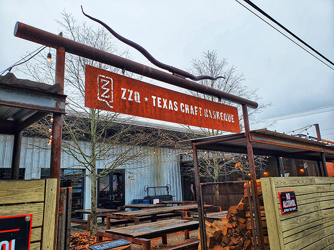 The rusted metal sign hanging above ZZQ's entrance isn't just decoration&mdash;it's a promise of authentic Texas flavor waiting just beyond those wooden picnic tables.