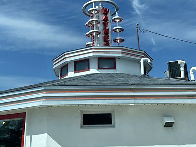 The unmistakable silhouette of Wayne's Drive-In stands against a perfect Wisconsin sky, its iconic neon sign promising burger bliss to all who approach.