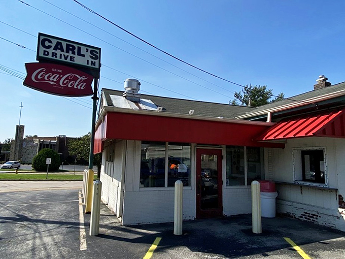 The iconic red and white exterior of Carl's Drive-In stands as a time capsule on Manchester Road, complete with its vintage Coca-Cola sign that's been guiding hungry travelers since the 1950s.