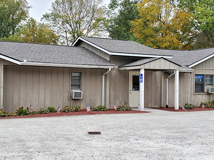 The iconic orange sign beckons hungry travelers like a burger lighthouse. This unassuming blue building houses flavor treasures worth the drive.