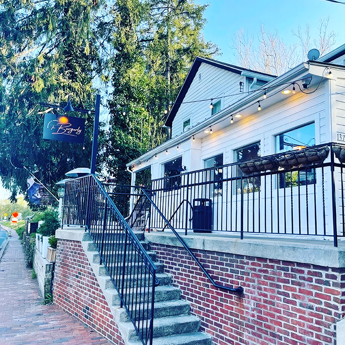 The white clapboard charm of The Burgerly beckons from the street, those vibrant red umbrellas promising shade for your burger-induced bliss.