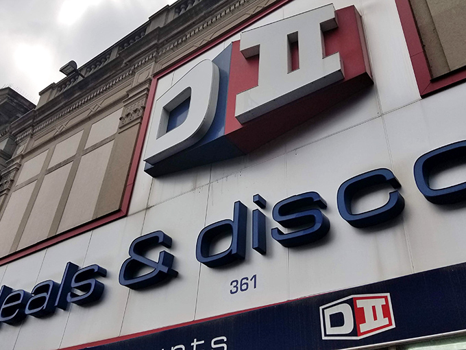 The blue and red signage of DII Deals & Discounts beckons like a siren song to bargain hunters navigating the urban landscape of Jersey City.