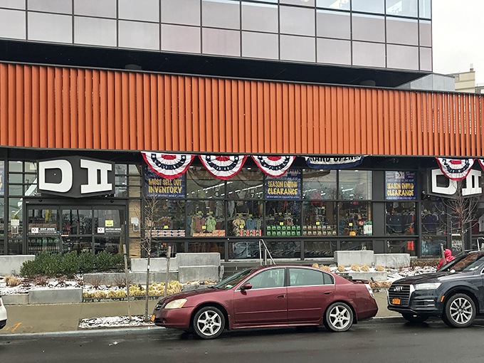 The distinctive orange-trimmed exterior of DII beckons bargain hunters like a retail oasis in Sheepshead Bay, complete with patriotic bunting and clearance promises.